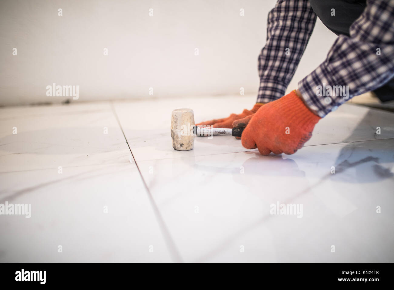 The worker's hand is knocking rubber hammer on the tile for better ...