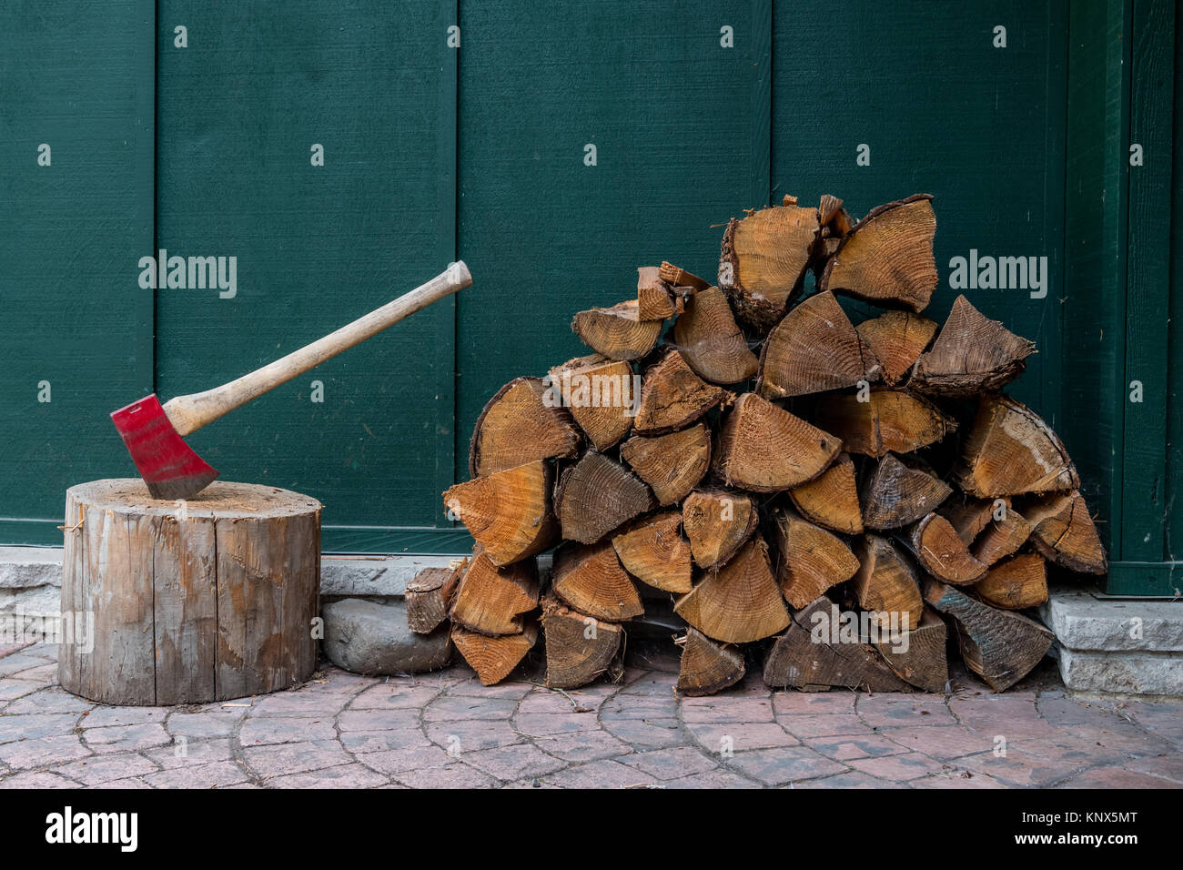 Red Axe and Pile of Fire Wood in front of dark green wall Stock Photo ...