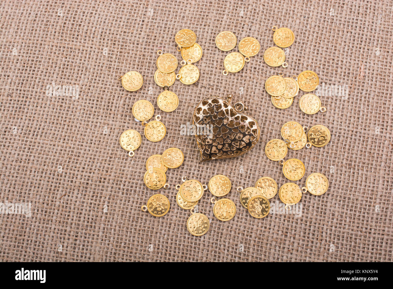 Fake gold coins around gold color heart Stock Photo - Alamy