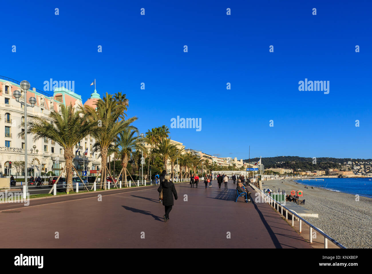 People walking in the sunshine on the seafront promenade parallel to ...