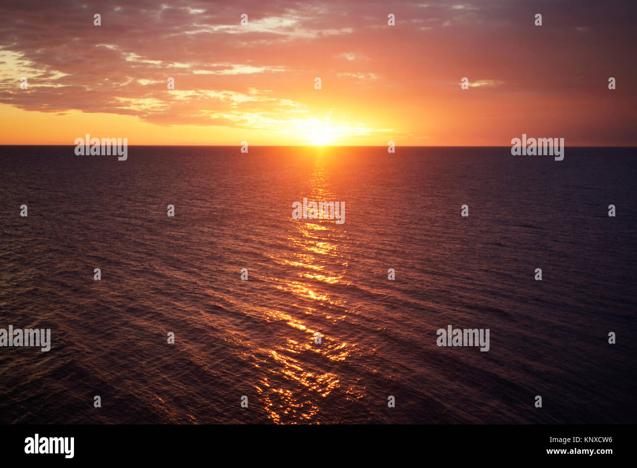 Pink and red sunset light from the sun on the sea Stock Photo - Alamy
