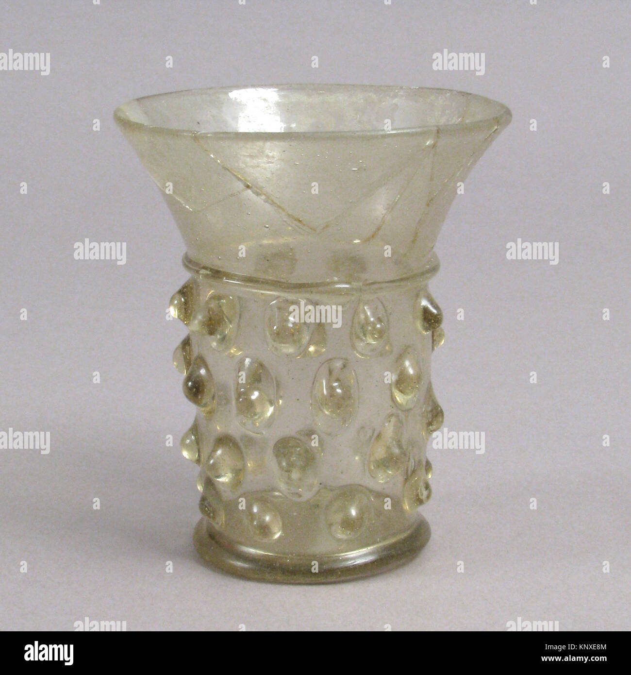 A historical glass beaker, preserved as a museum object, featuring a ...