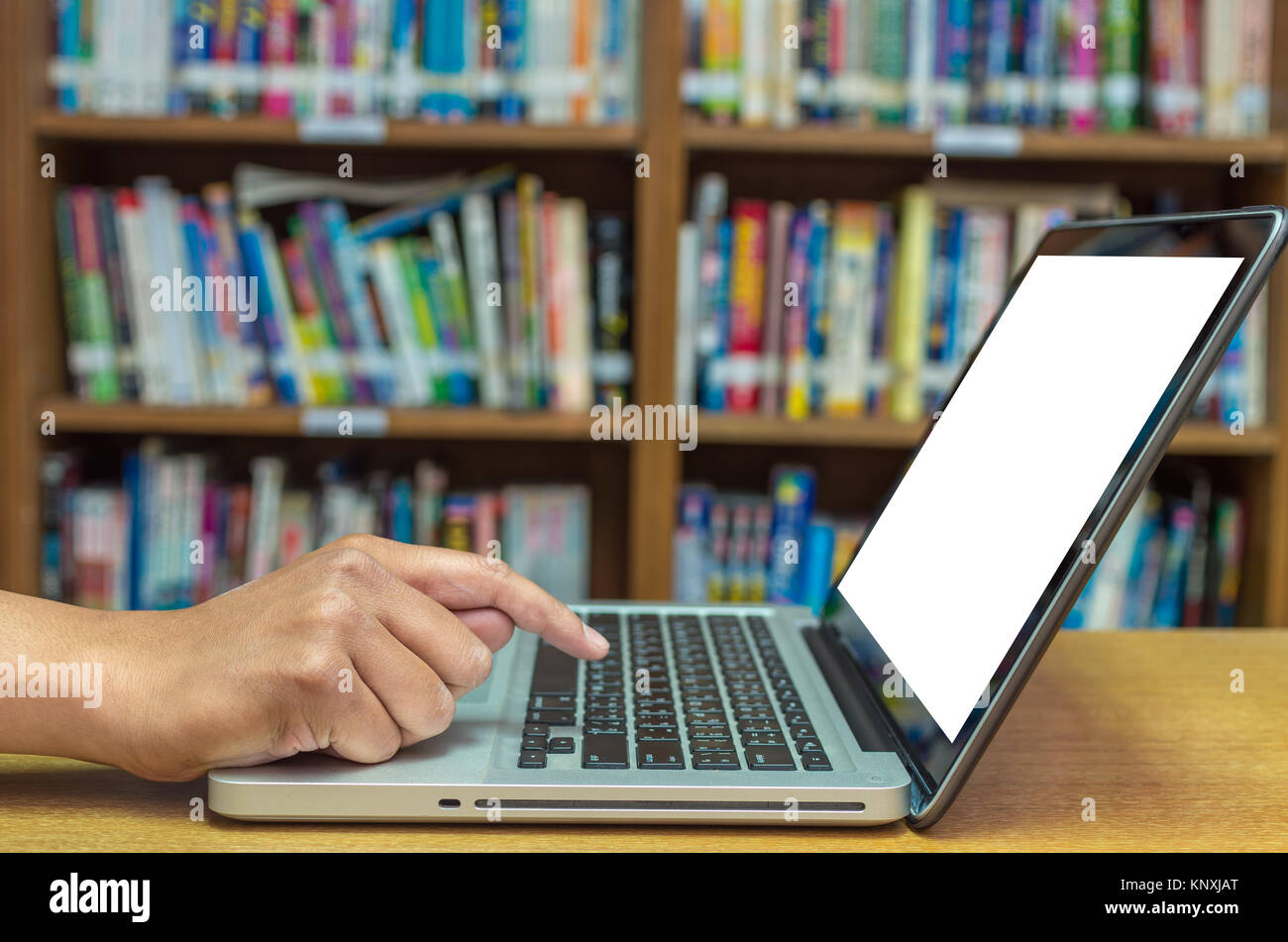 Hand typing on laptop computer over the wood table in library ...