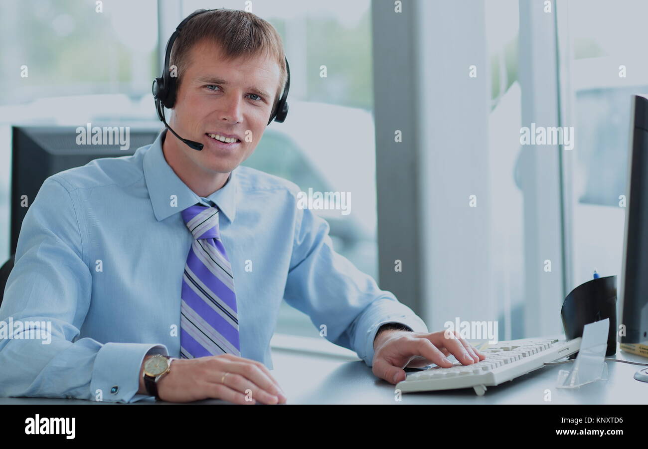 Happy young man working at callcenter, using headset Stock Photo - Alamy