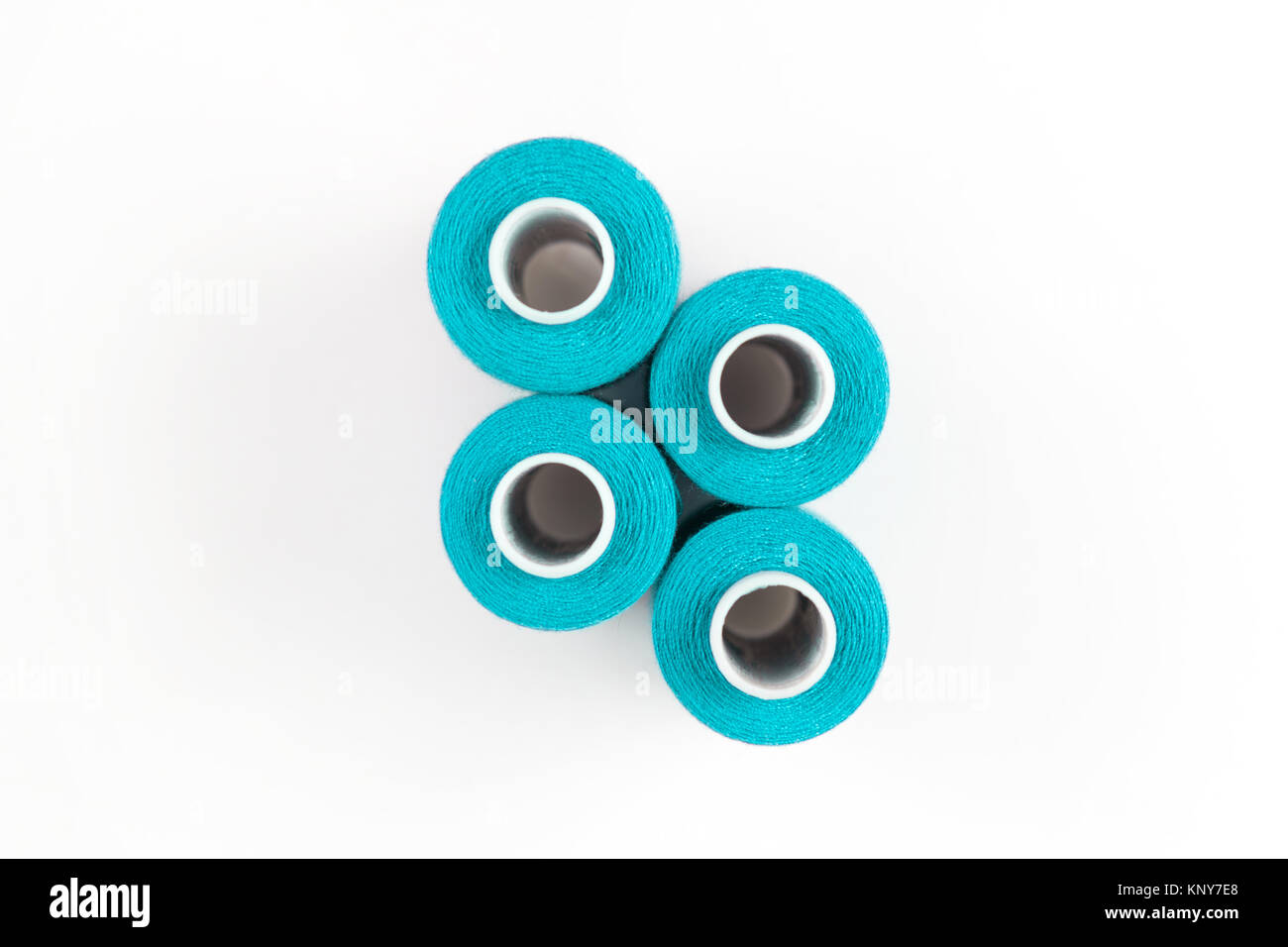 Four turquoise sewing threads on a white coils on a white background ...