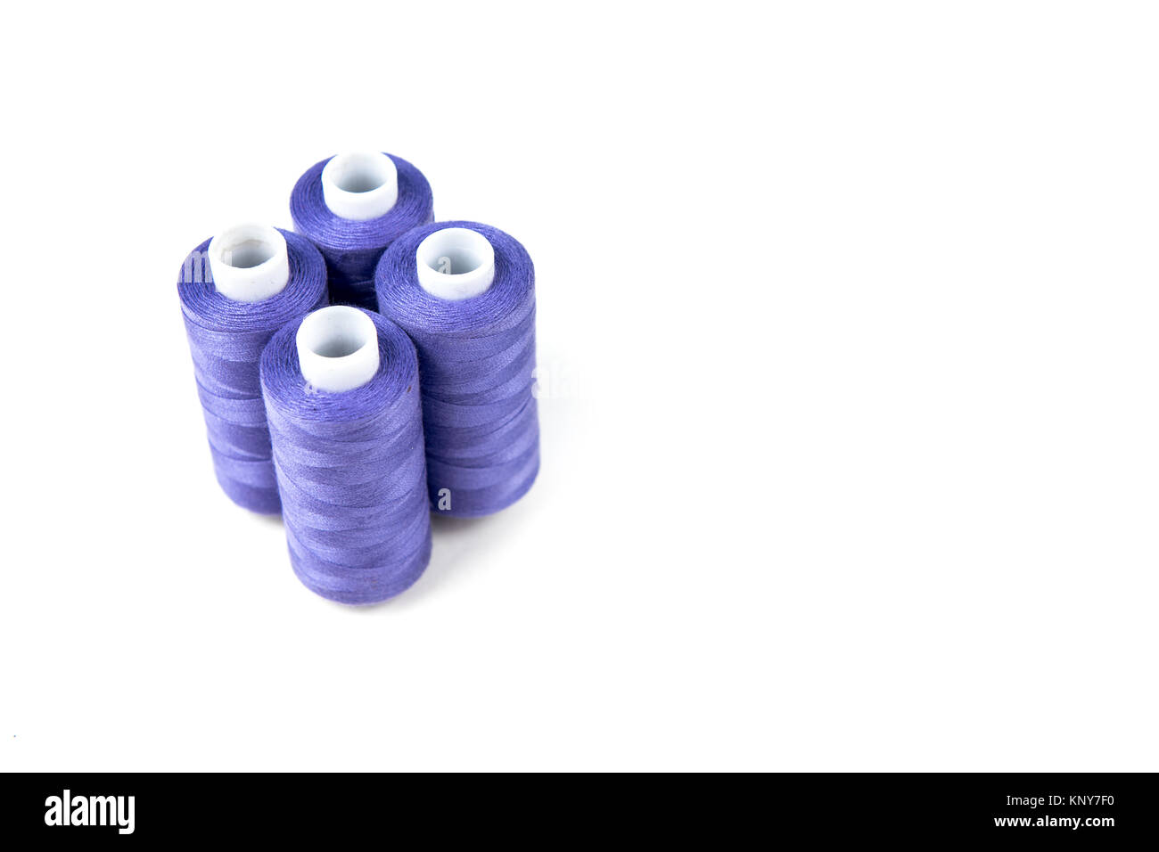 Four medium purple sewing threads on a white coils on a white ...