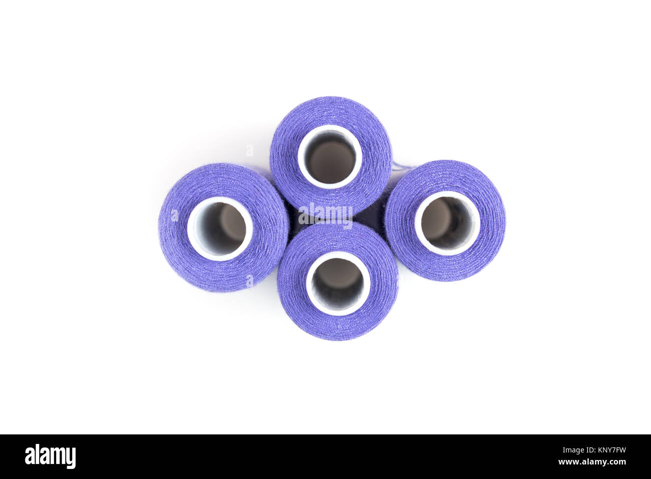 Four medium purple sewing threads on a white coils on a white ...