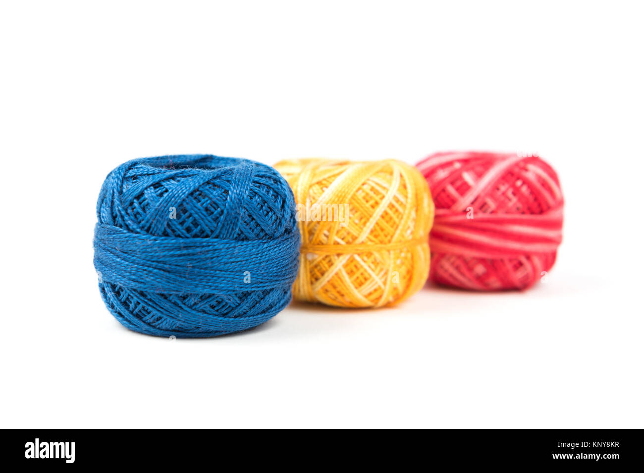 Three colored sewing threads in a row on a white background. Blue, red ...