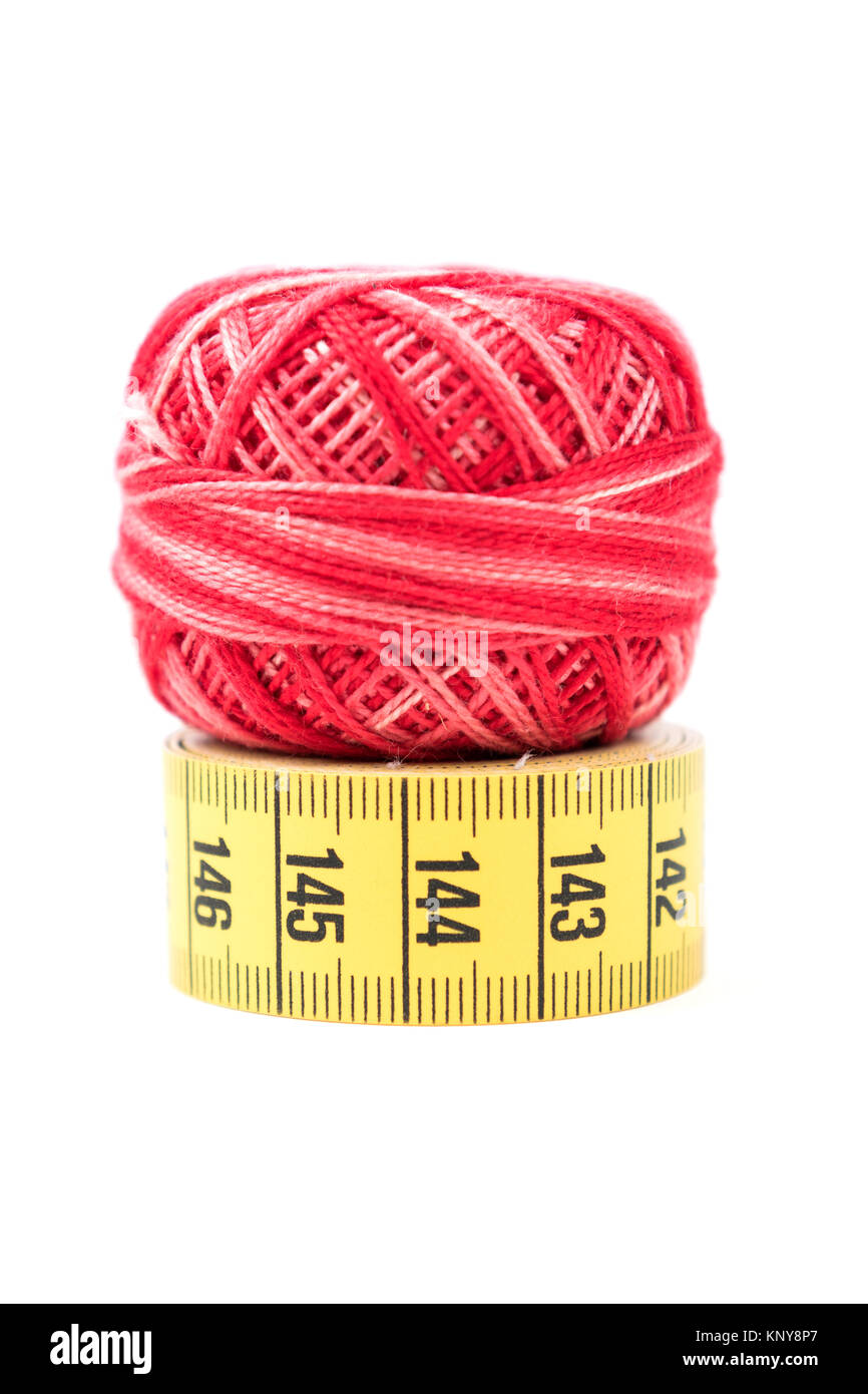Red sewing thread on top of yellow measuring tape. Sewing accessories ...