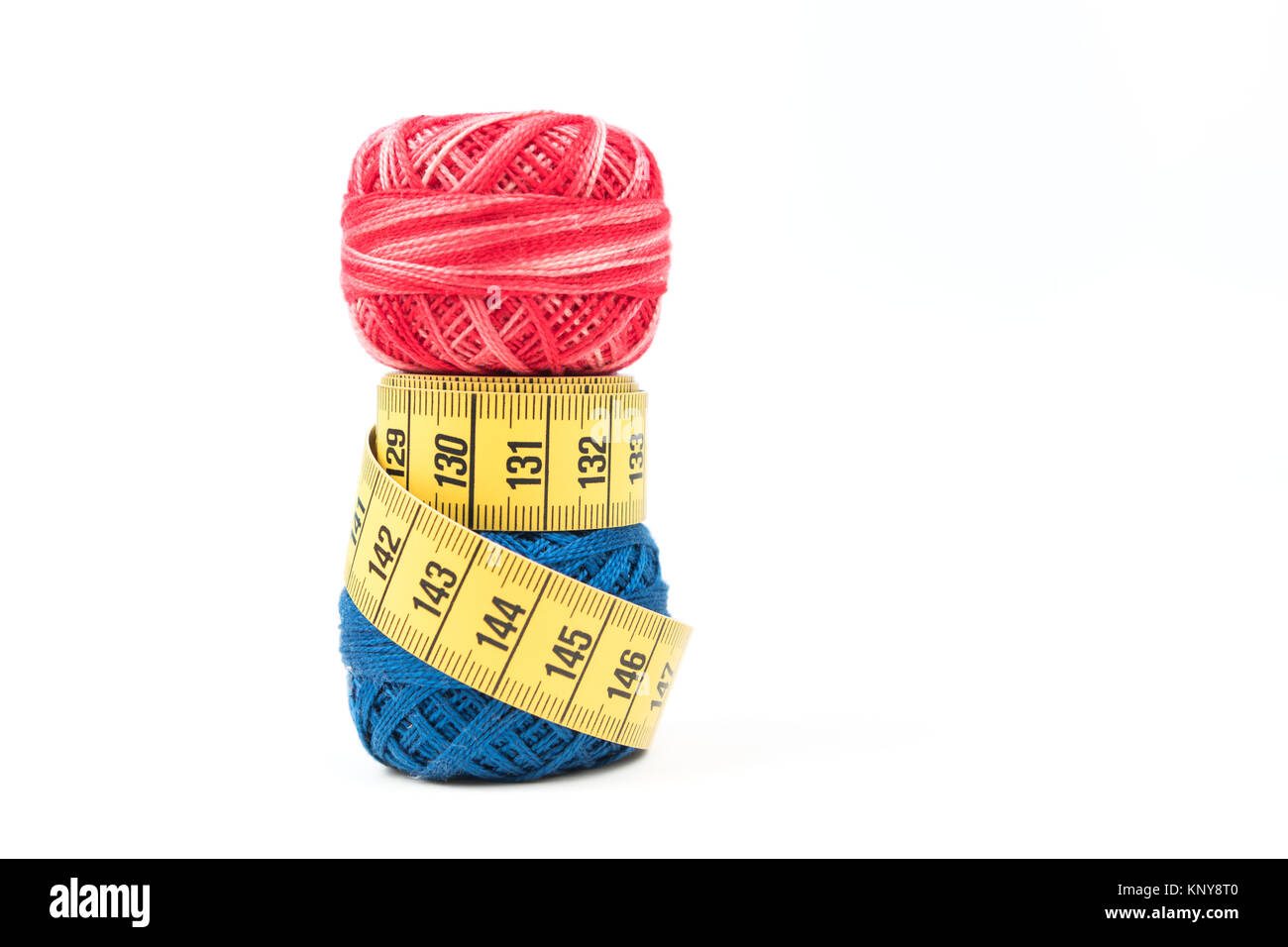 Blu and red sewing thread with yellow measuring tape on a white ...