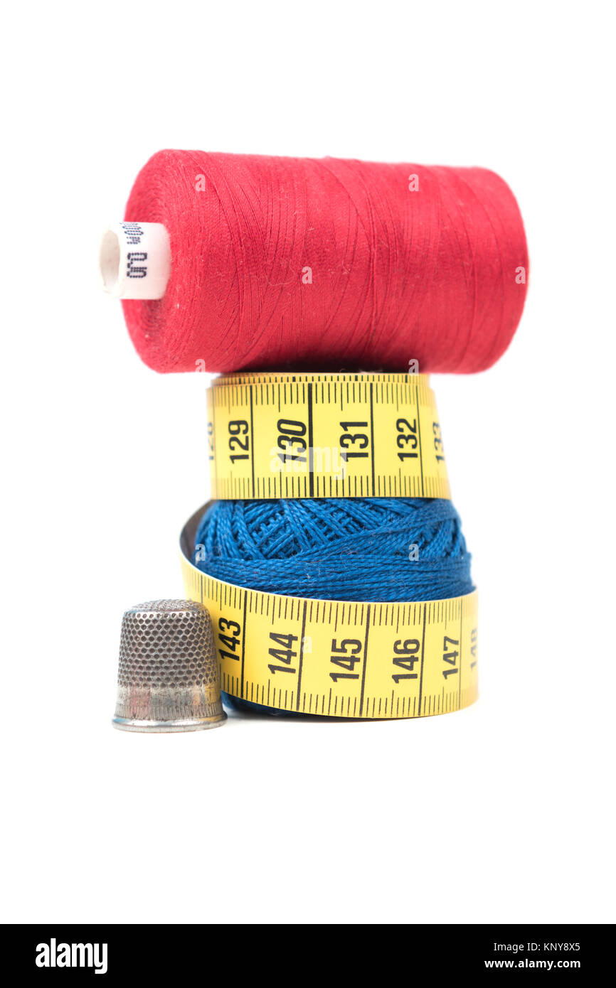 Blu and red sewing thread with yellow measuring tape and metal thimble ...