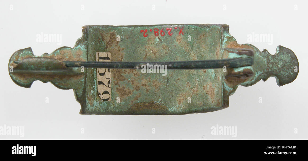 Bow-shaped metal brooch featuring pin and clasp, used for fastening ...