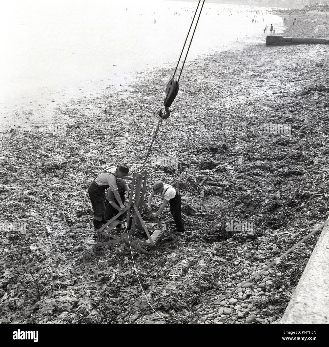 1950s, historical, male operatives on a beach using a wooden grab ...