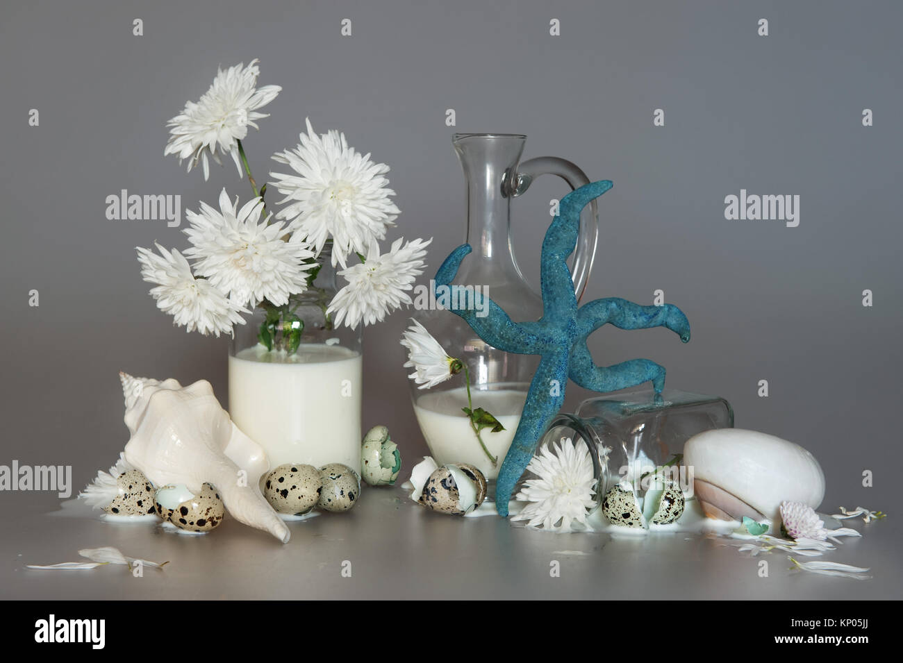 White aster flowers in a glass with milk, sea shells, quail eggs and a ...