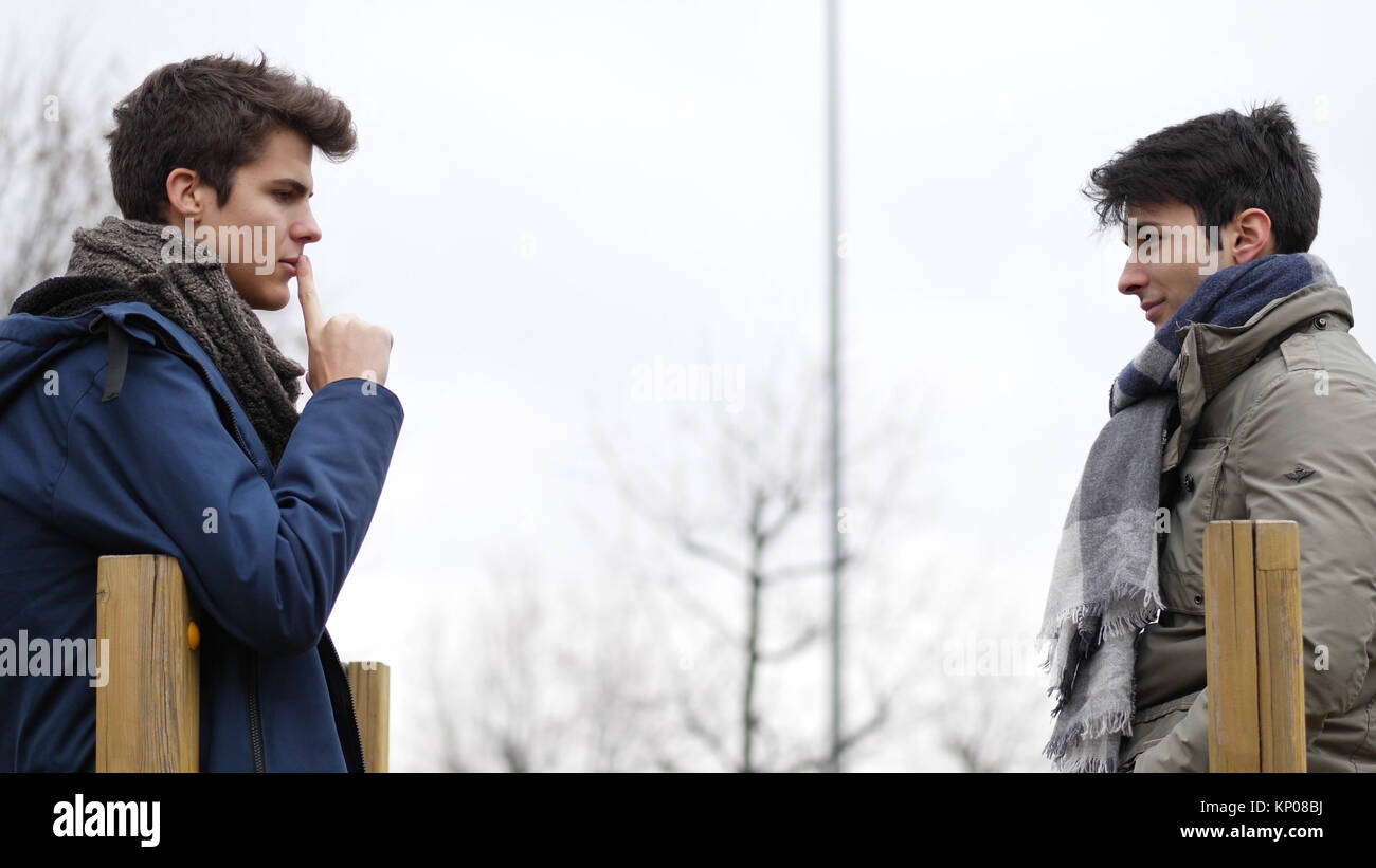 From below view of young men in winter clothing talking while chilling ...