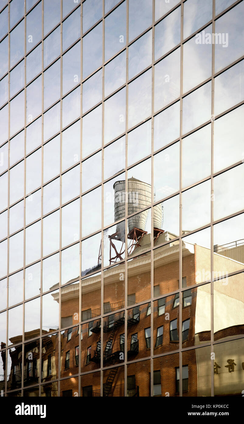 A traditional rooftop water tower in downtown New York reflected in the ...