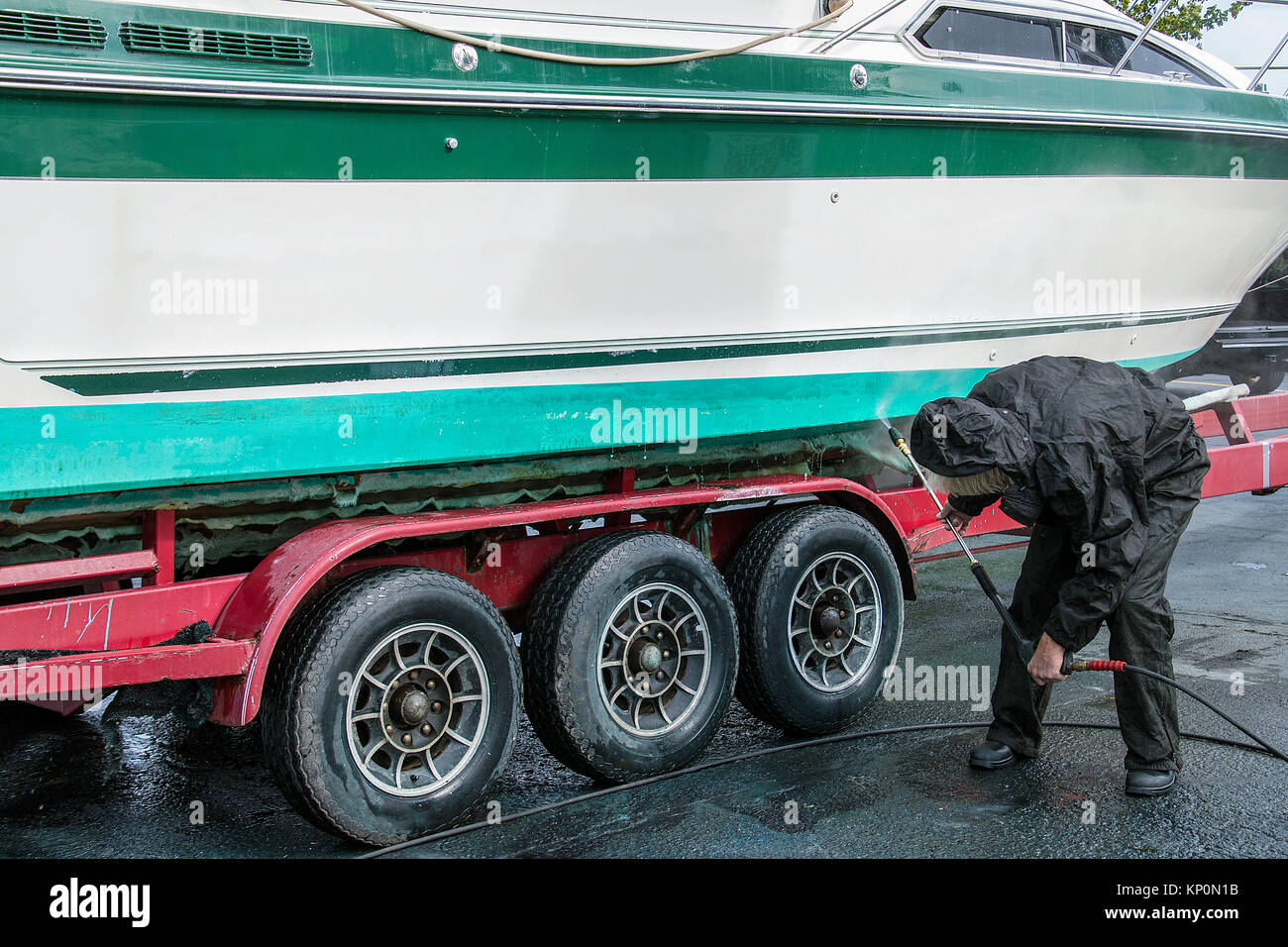 man in black waterproof suit power washing boat hull Stock Photo - Alamy