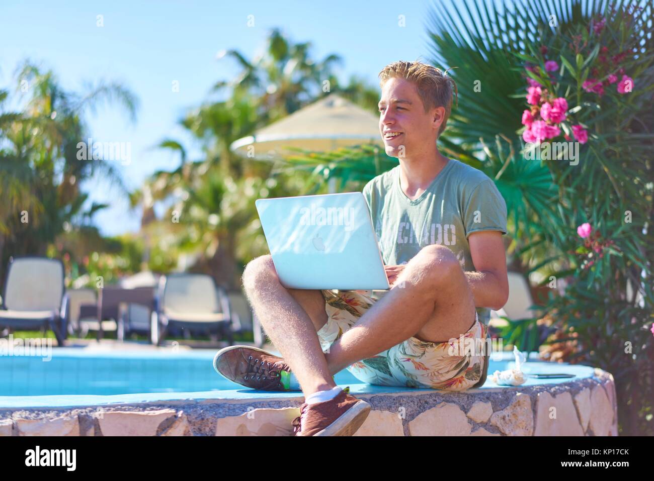 young man with laptop computer sitting in holiday destination Stock ...