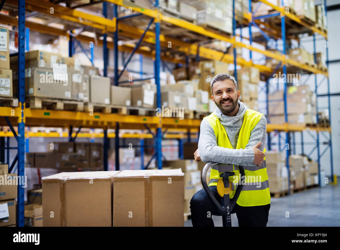 Male warehouse worker standing by a pallet truck Stock Photo - Alamy
