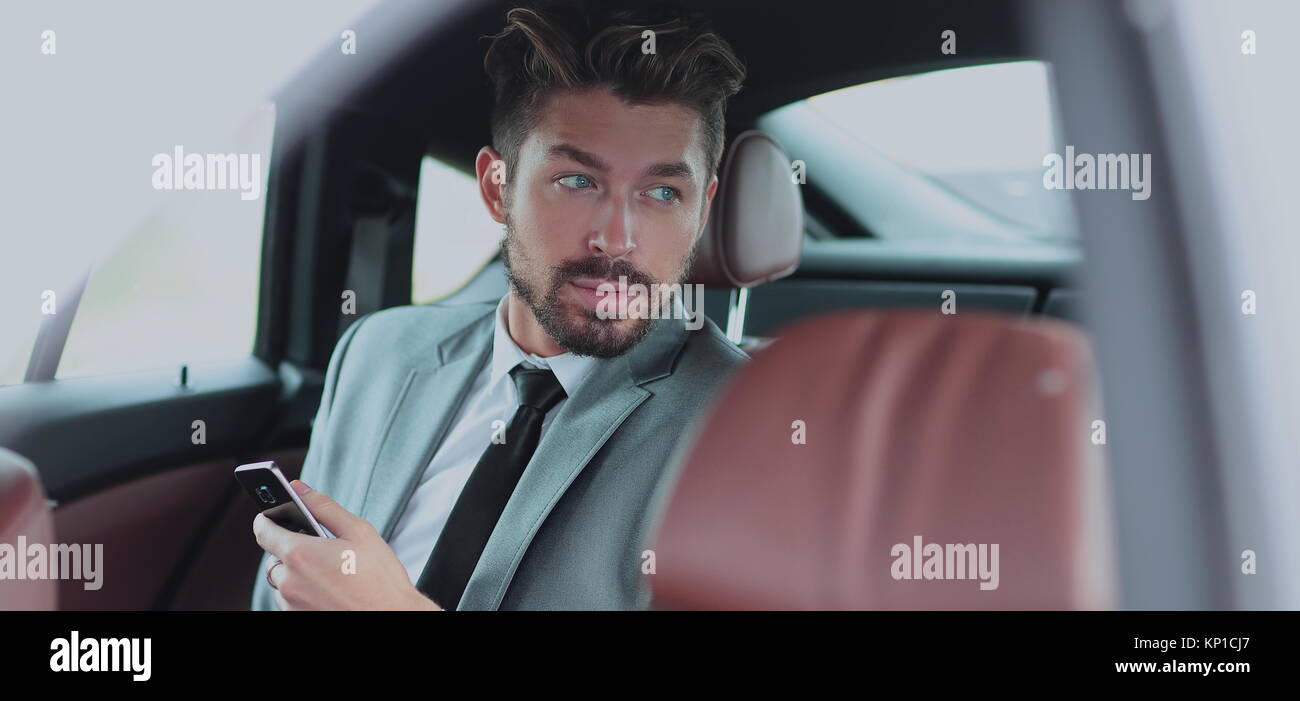 Happy young businessman using mobile phone in back seat of car Stock ...