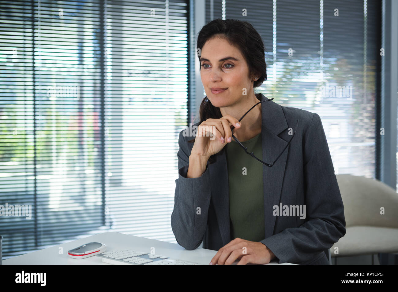 Thoughtful female executive sitting at desk in office Stock Photo - Alamy