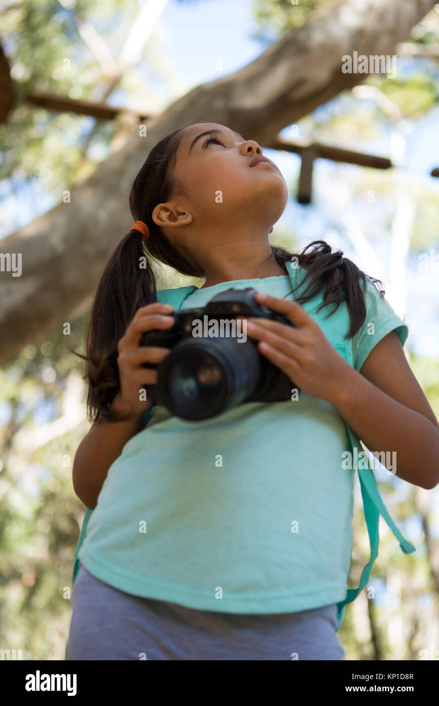 Little girl with backpack holding dslr camera in her hand looking up in ...