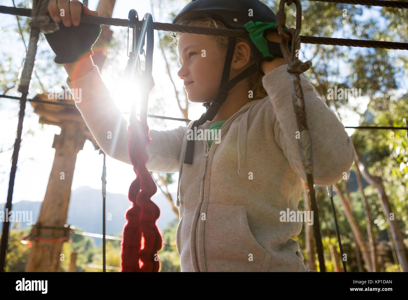 Little girl wearing helmet standing near zip line in the forest Stock ...