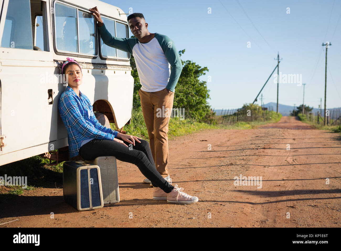 Young couple sitting on suitcase at countryside Stock Photo - Alamy