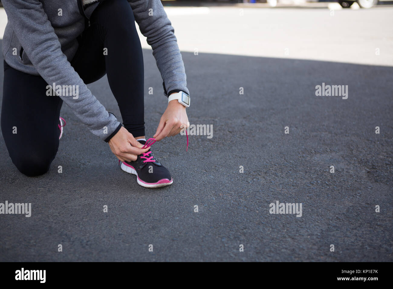 Female jogger tying her shoe laces on a sunny day Stock Photo - Alamy