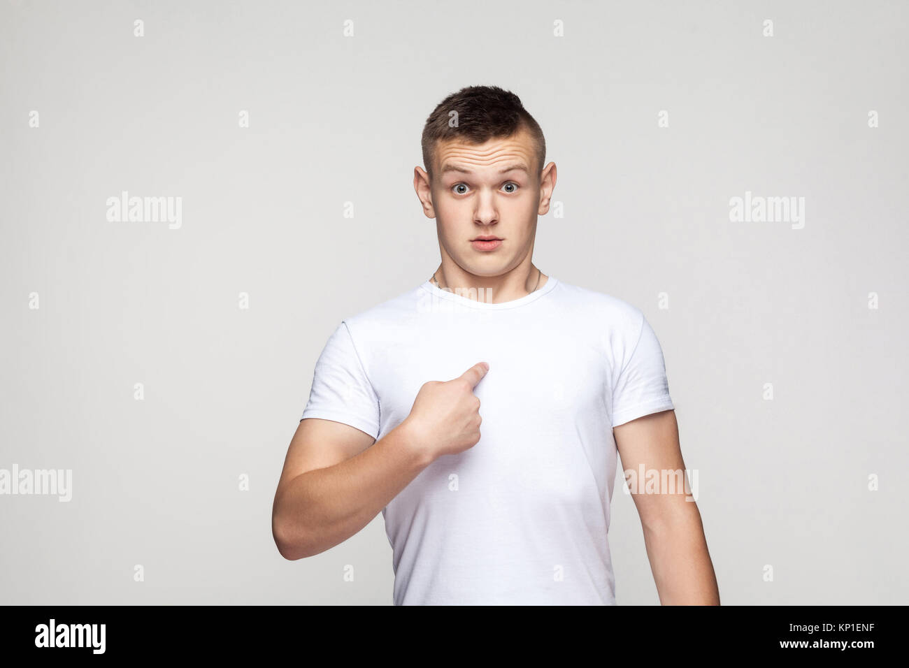 Surprised boy looking at camera and pointing finger himself. Studio ...