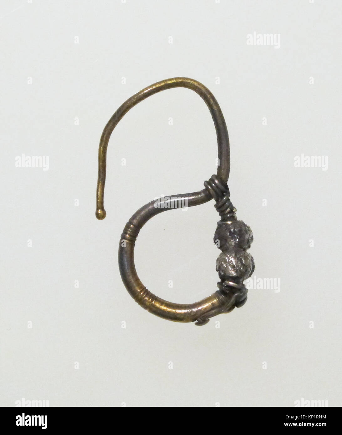 An ancient delta-shaped earring featuring bead decorations ...