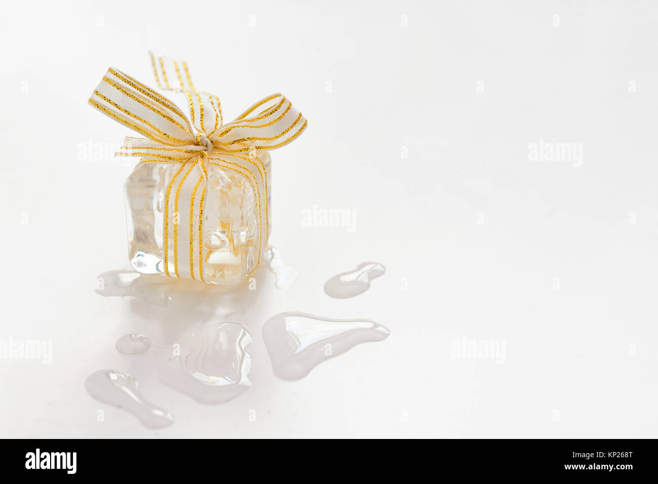 Melting Ice cube gift on white table Stock Photo - Alamy