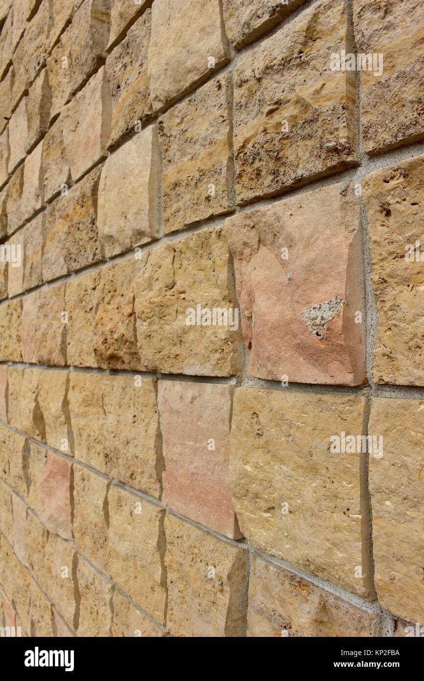 Angled view of a stone wall background comprised of textured square ...