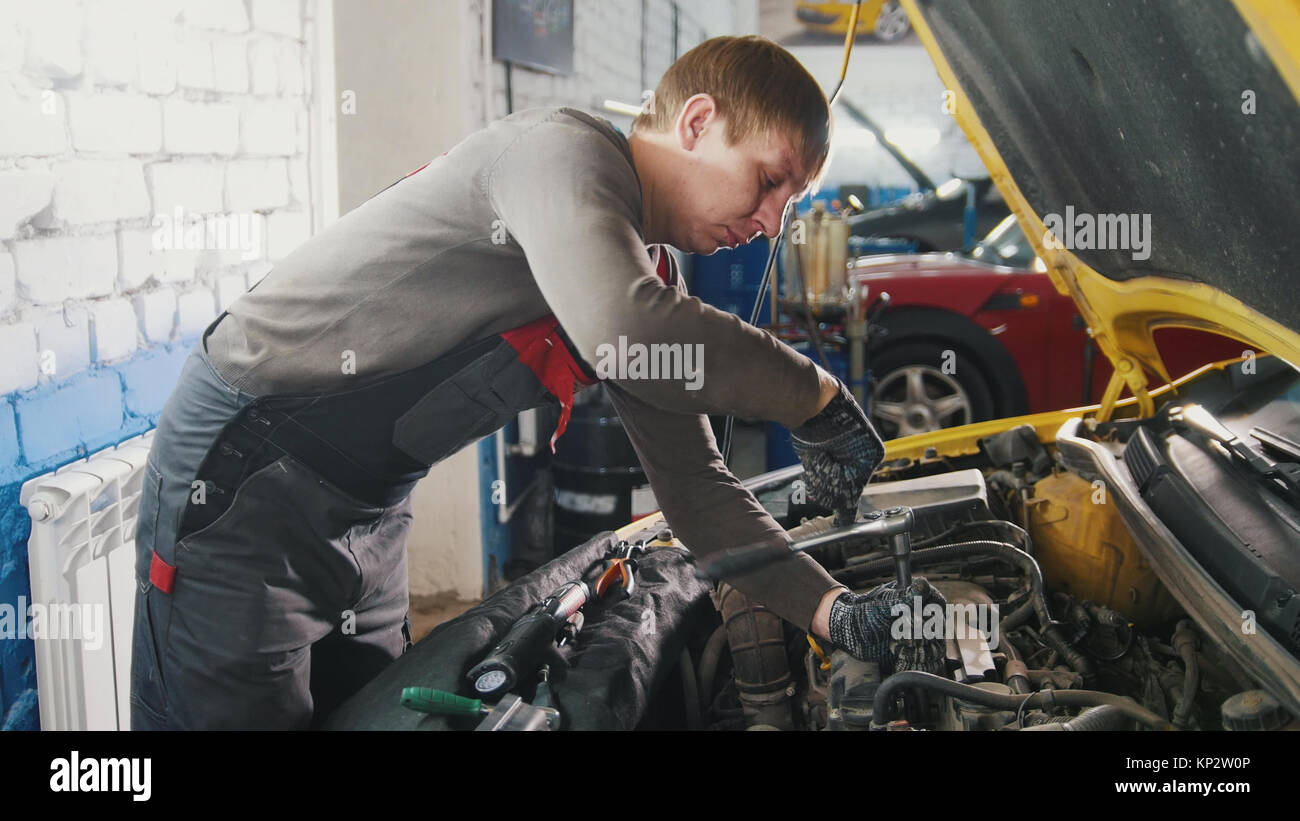 Mechanic in car repairing service - diagnostics in engine compartment ...