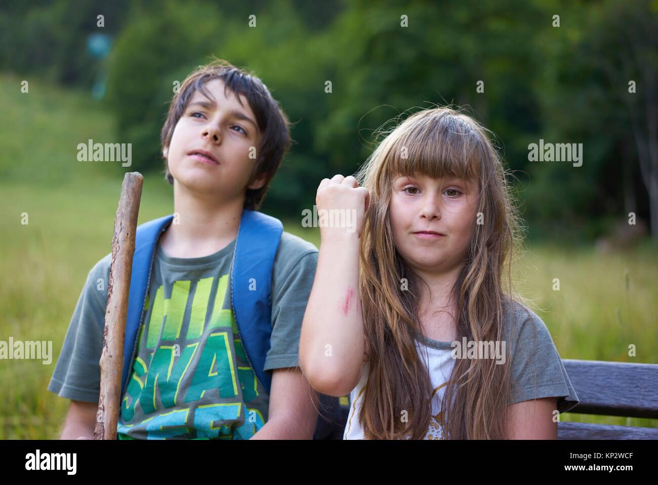 chilled brother and sister sitting on a bench Stock Photo - Alamy