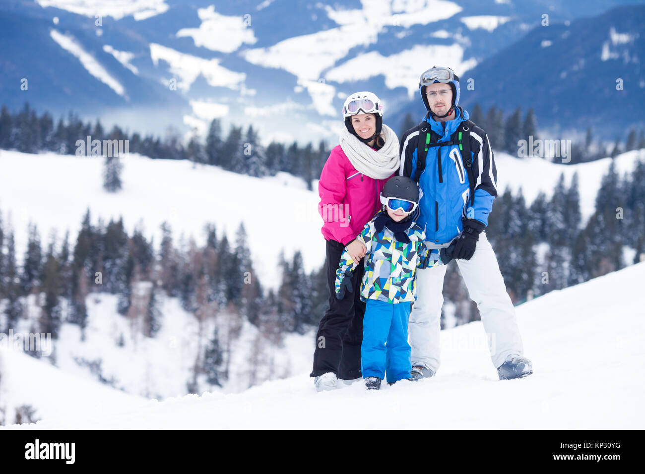 Young happy family with one child, skiing in the mountains, wintertime ...