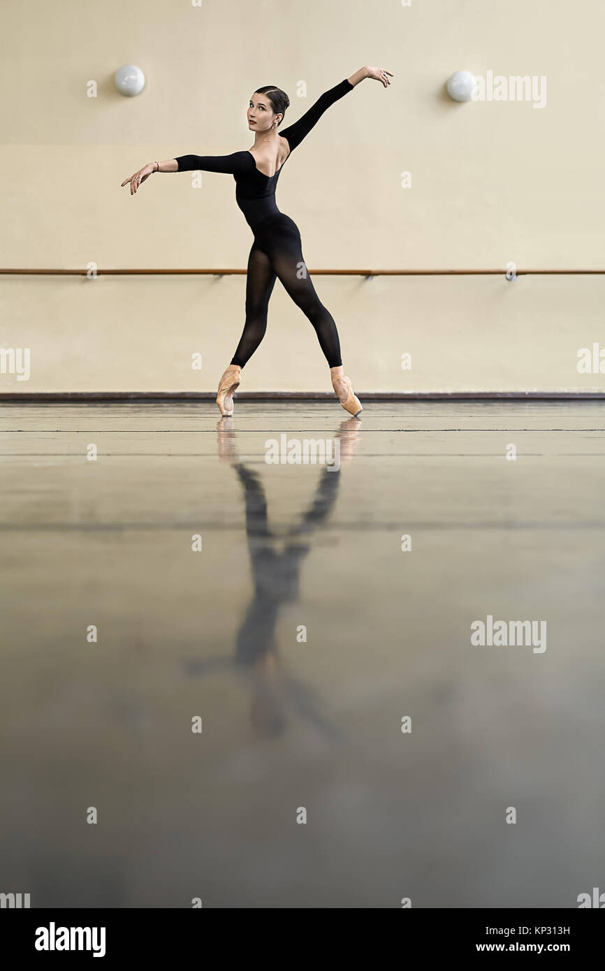 Gorgeous ballerina stands on the toes in the dance hall. She wears a ...