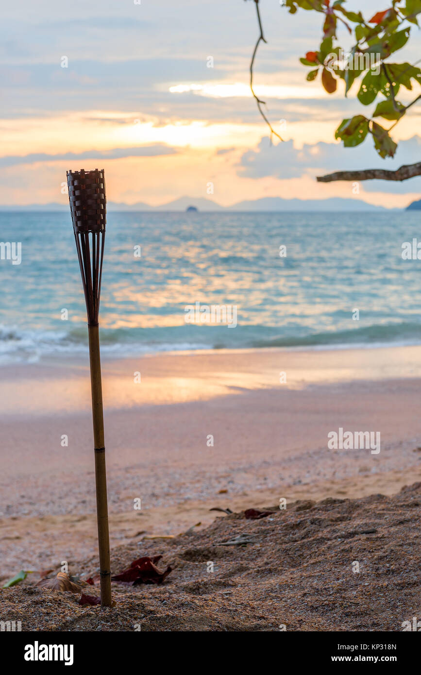focus on the torch on the sandy beach of Thailand and the sunset on the ...