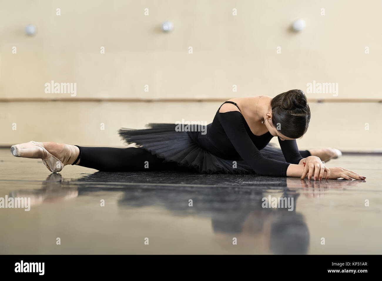 Young ballerina does a split on the glossy floor in the dance hall. She ...