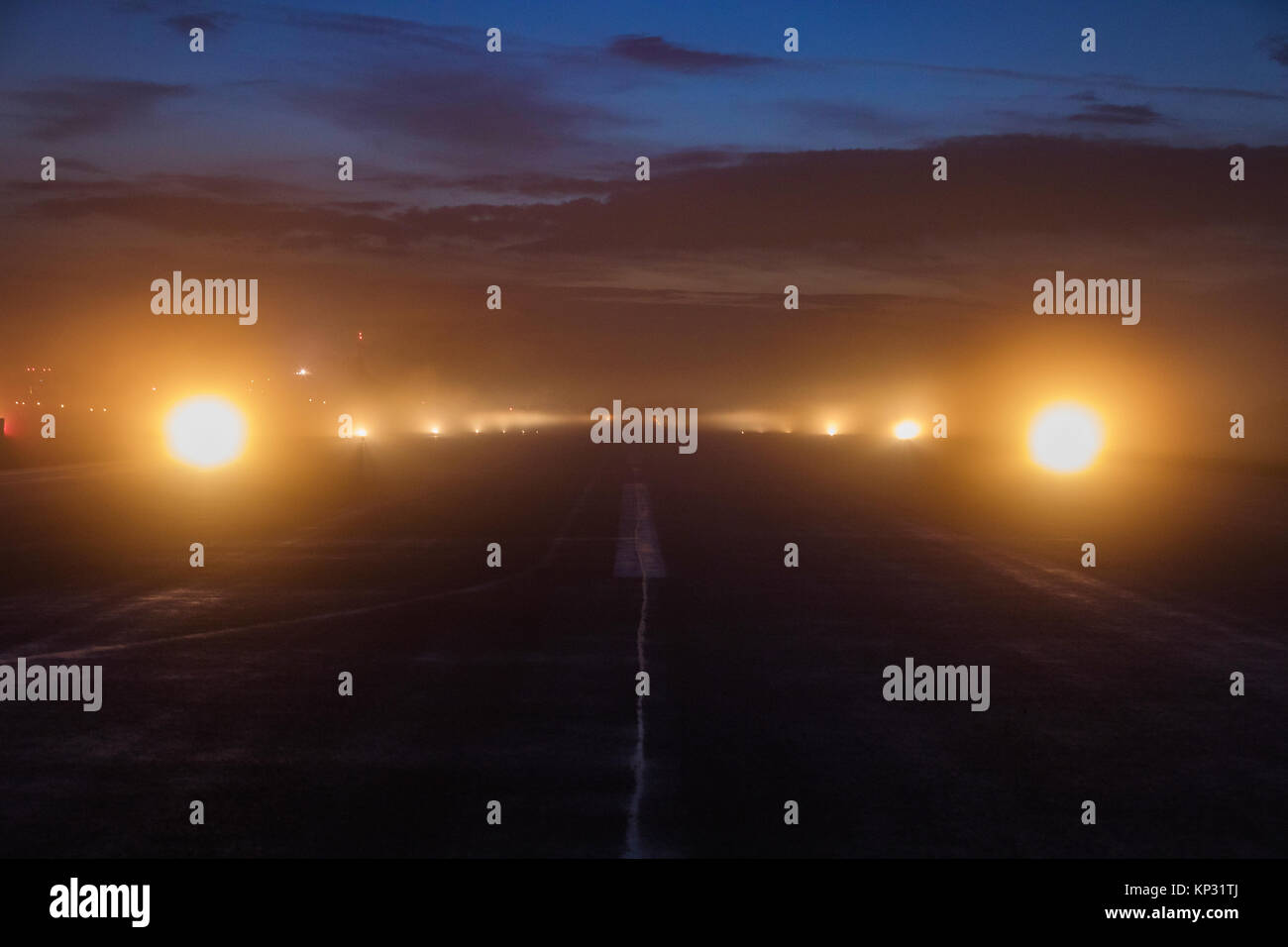 Empty runway at airport during a foggy evening. Illuminated runway on a ...
