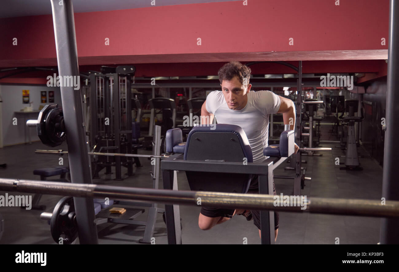 one young man, dip exercise, dark gym indoors. full lenght body shot ...