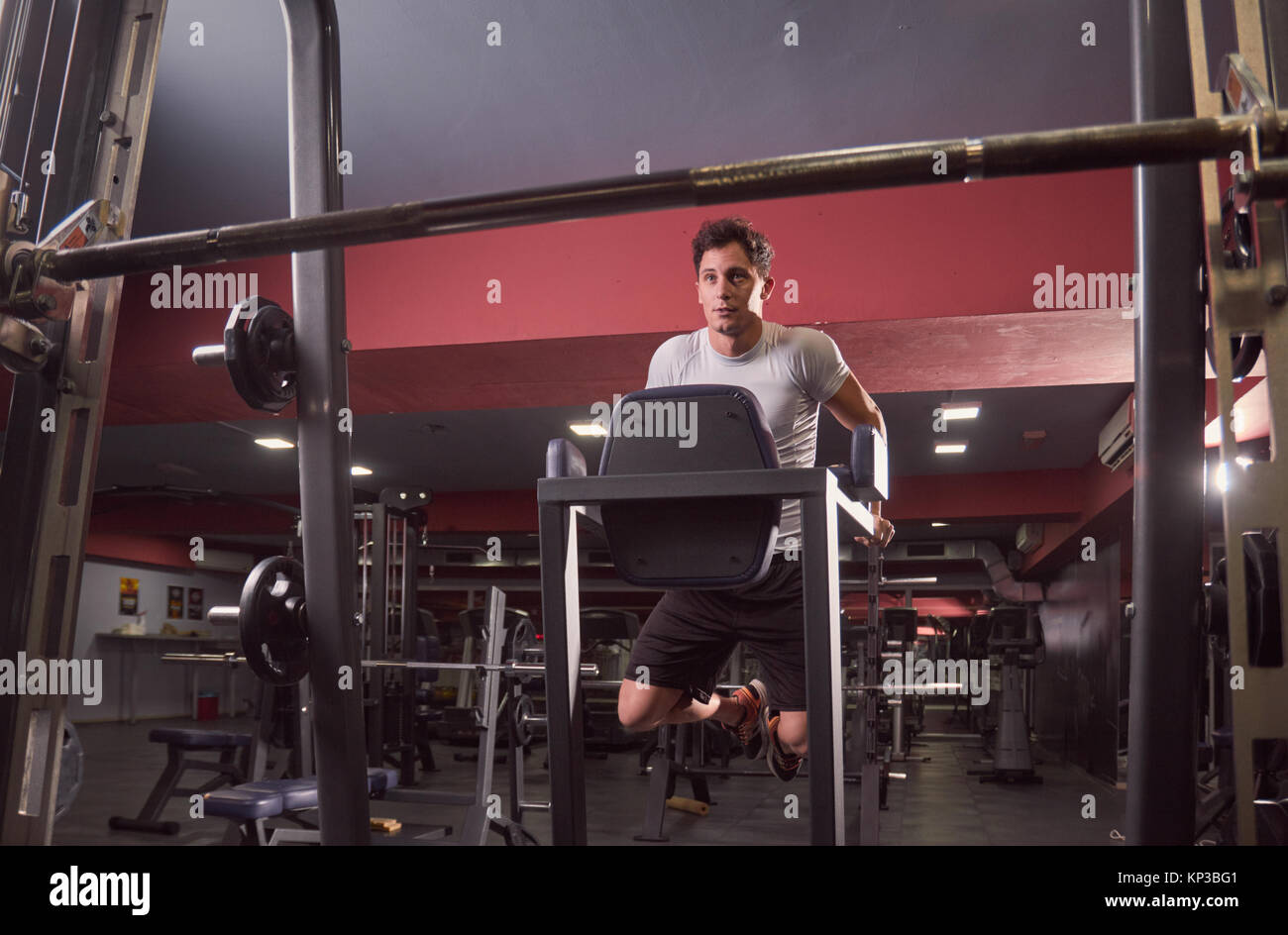 one young man, dip exercise, dark gym indoors. full lenght body shot ...