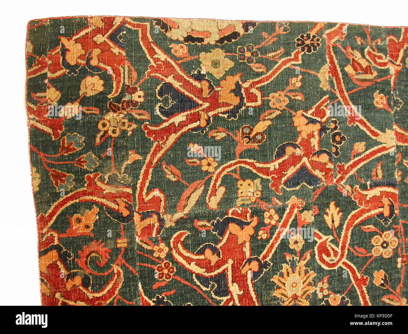 A blue-ground carpet fragment shows scrolling floral vine motifs ...