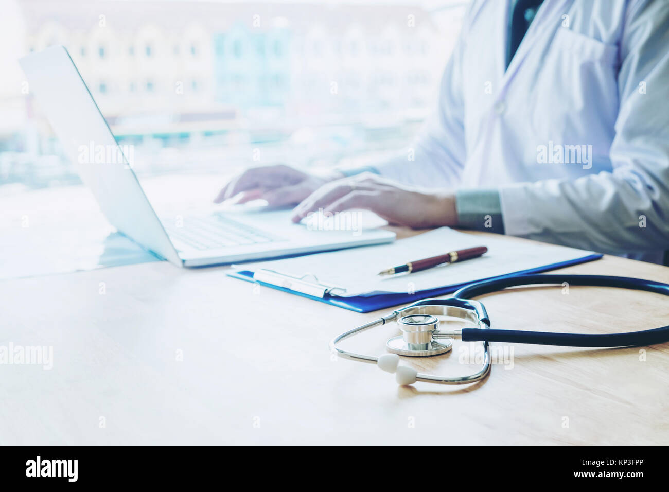 Doctor typing information on Laptop in Hospital office focus on ...