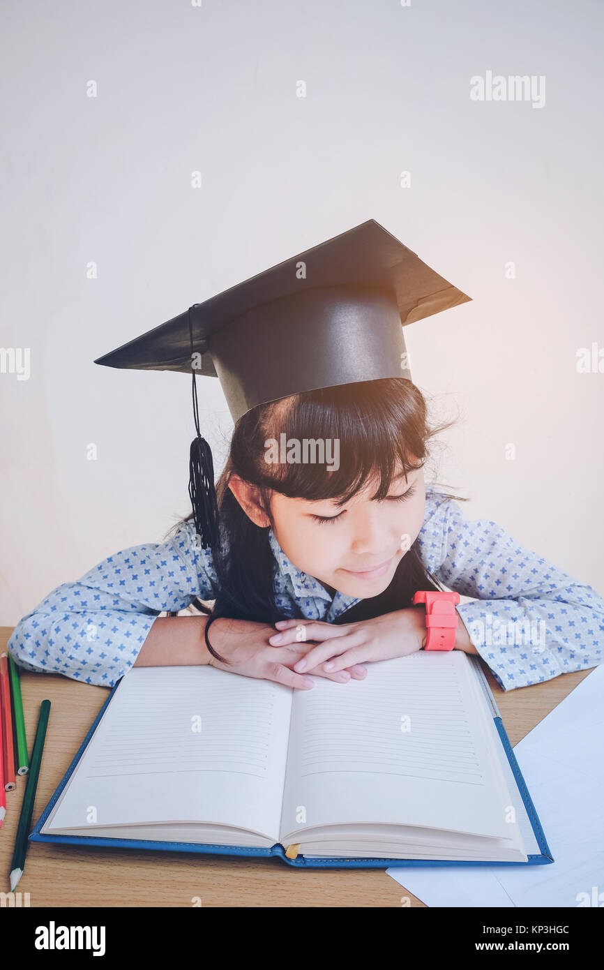 Asian school kid in graduation cap and reading a book Stock Photo - Alamy