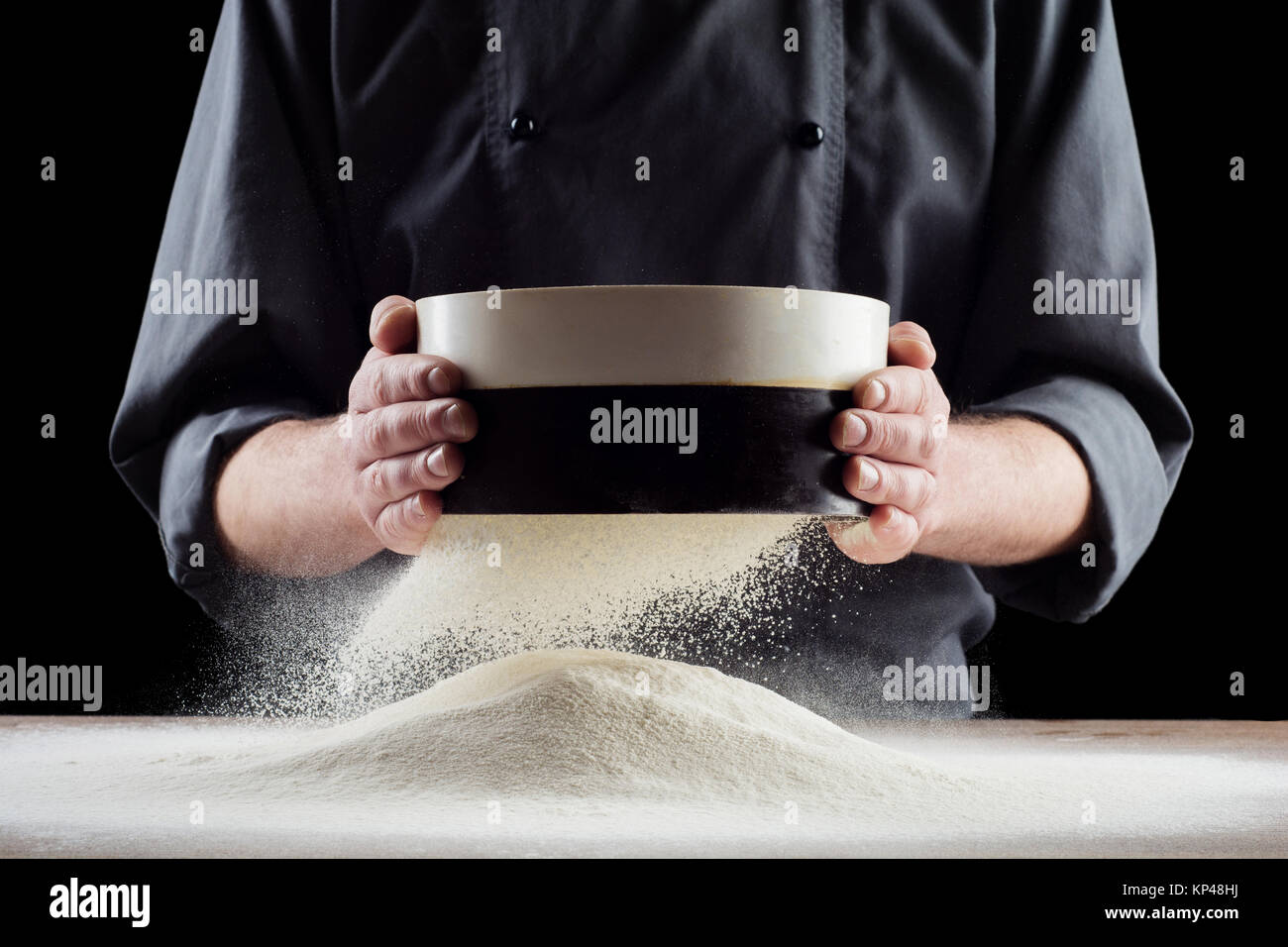 Male hands sifting flour from old sieve on old wooden kitchen table ...