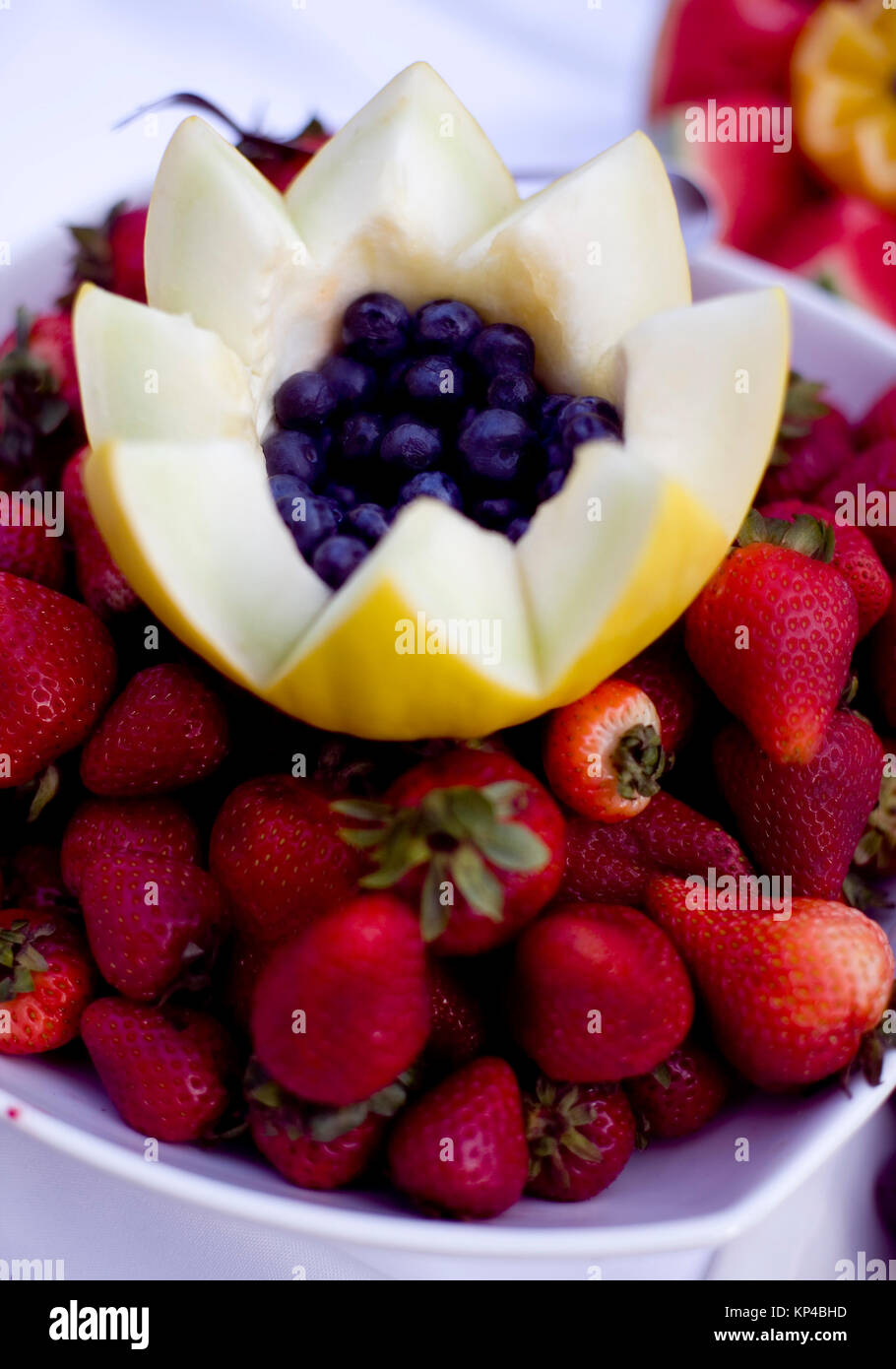 blue berries sit inside a cut melon on top of a plate full of ...