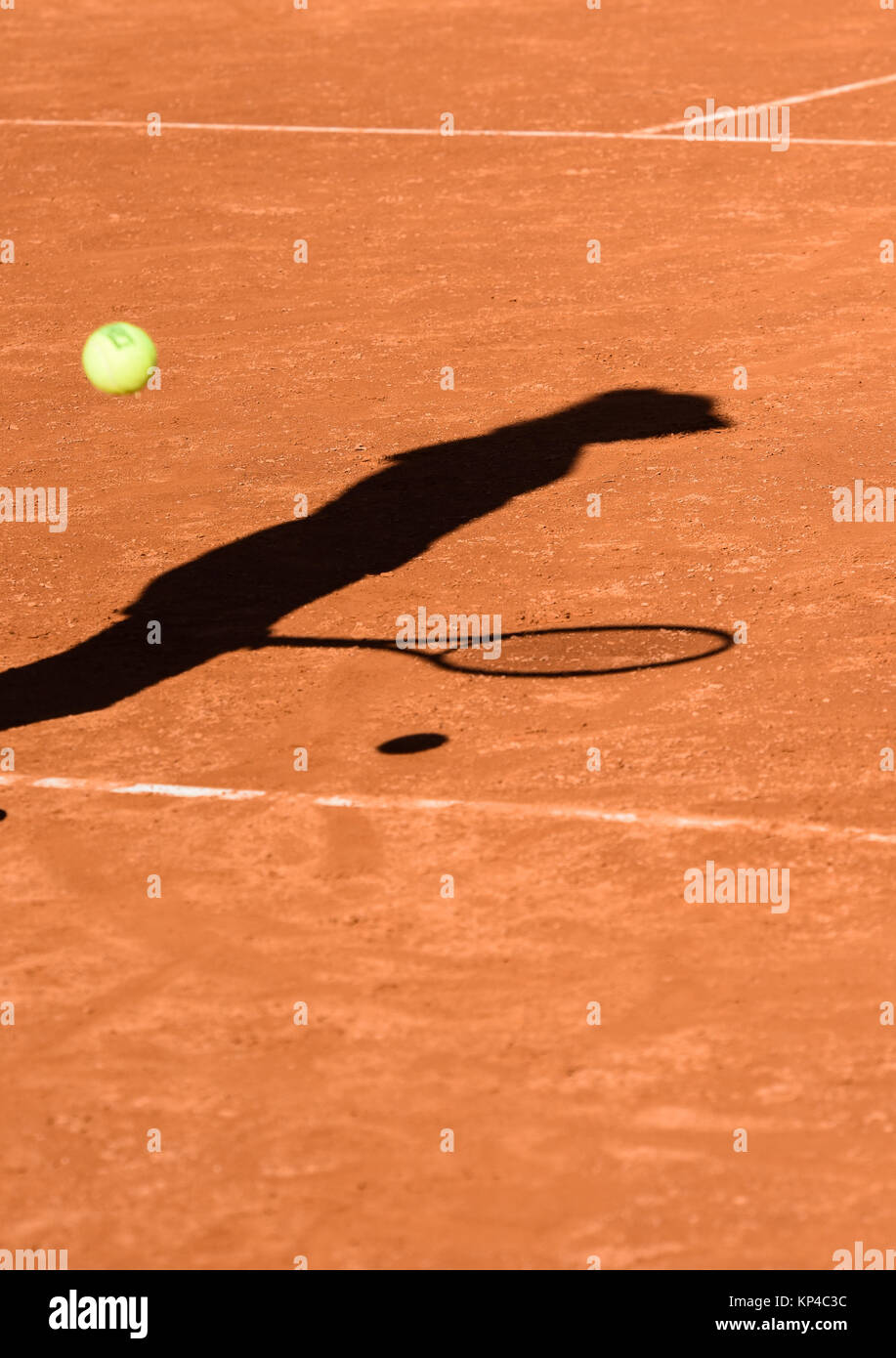 Tennis, the shadow of a tennis player throwing a ball in the red sand ...