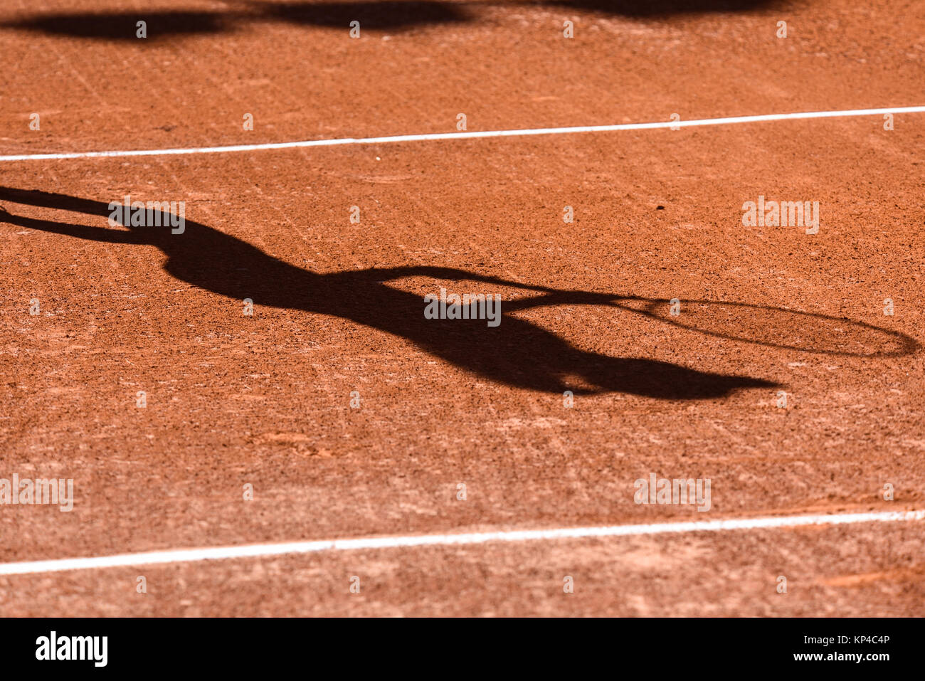 Tennis, the shadow of a tennis player throwing a ball in the red sand ...