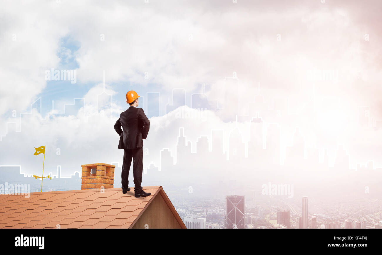 Engineer man standing on roof and looking away. Mixed media Stock Photo ...